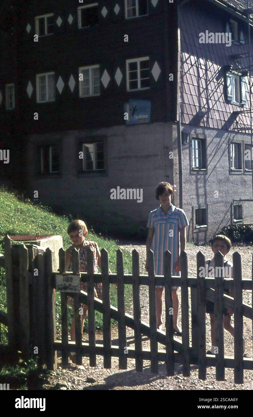 A mother with two children stands on the yard of a farmhouse behind a ...