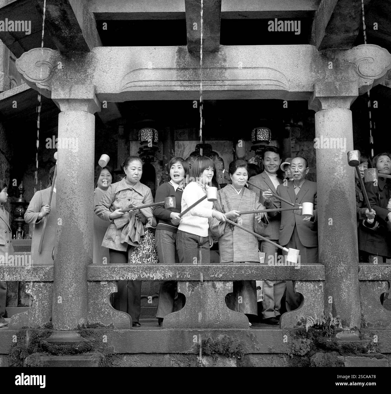 Japanese at a religious ceremony where water is poured down from above ...
