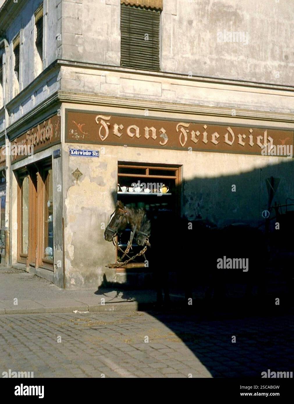 A horse-drawn carriage stands in the shade in front of a shop on the ...