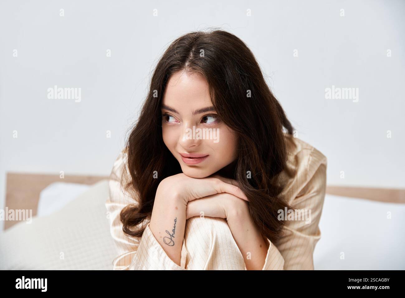 A beautiful young woman rests her chin on her hands, radiating calmness ...