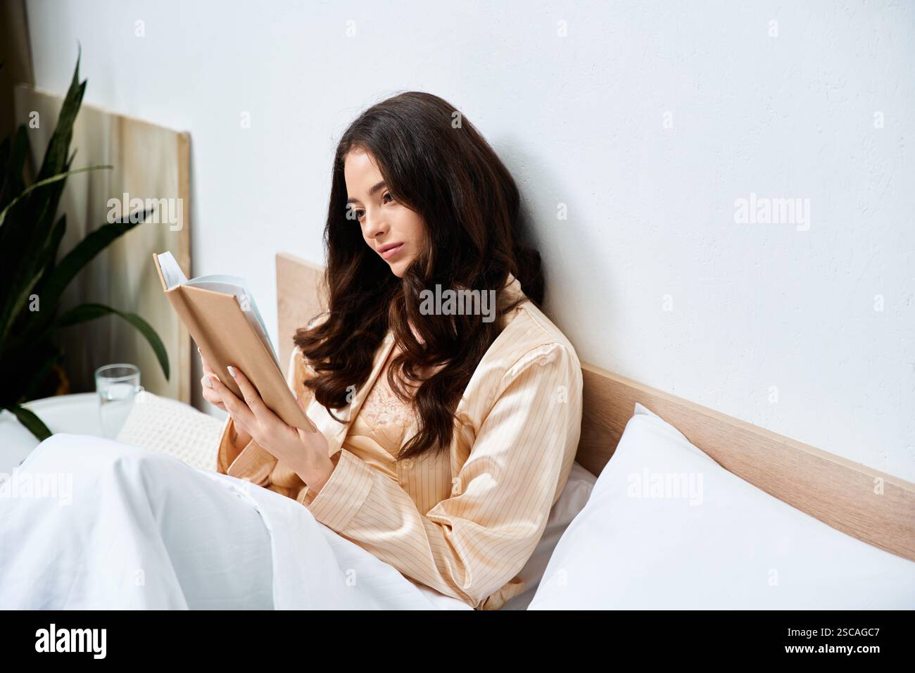 A beautiful young woman enjoys a moment of peace as she reads a book in ...