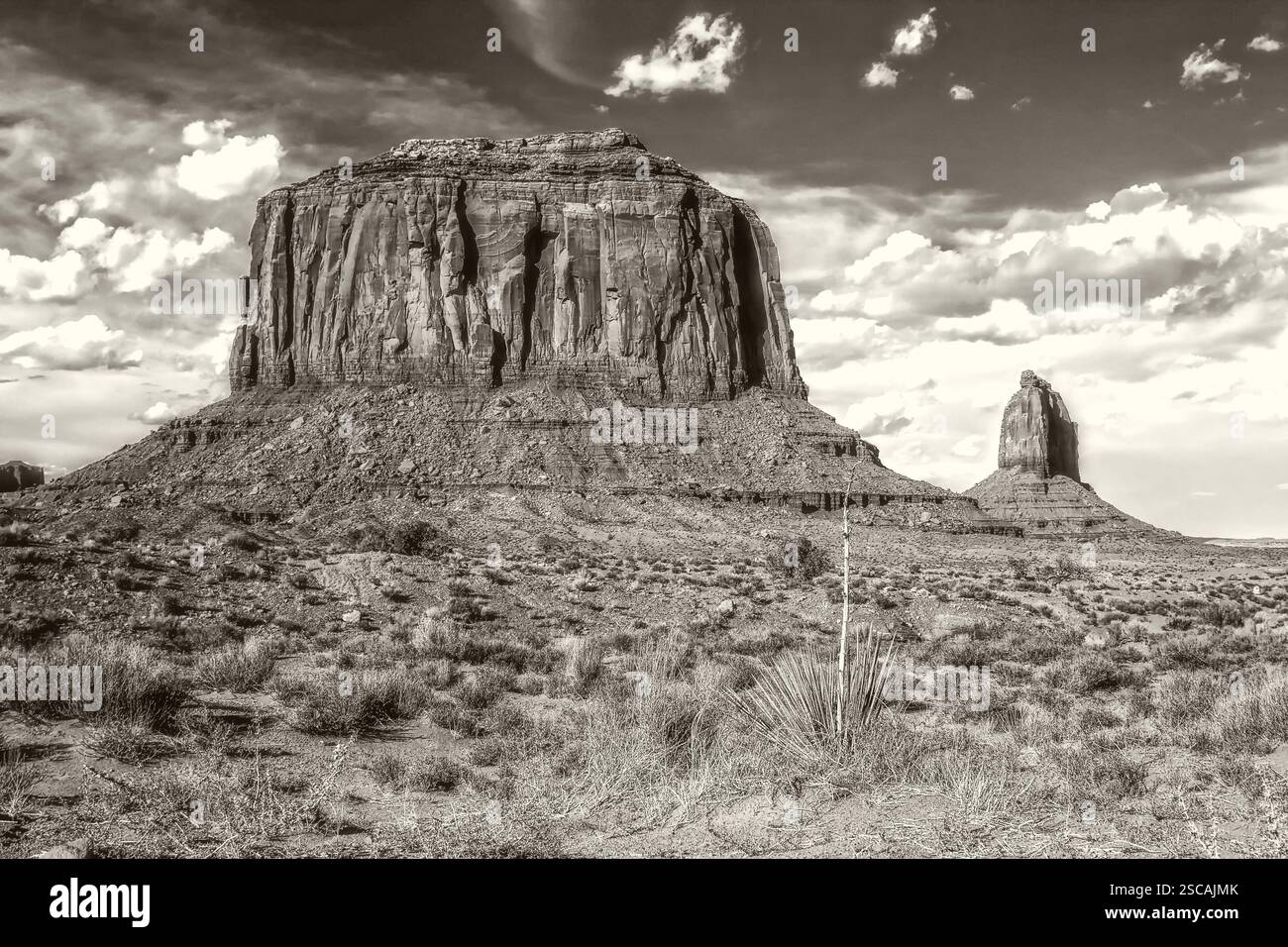 A large rock formation in the desert. The sky is cloudy and the sun is ...
