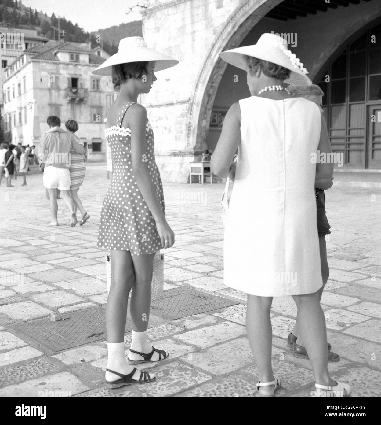 Mother and daughter wearing a dress and the same hat on a square in ...
