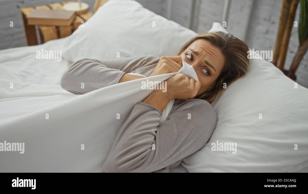 Woman lying in bed looking anxious with a blanket, expressing fear, in ...