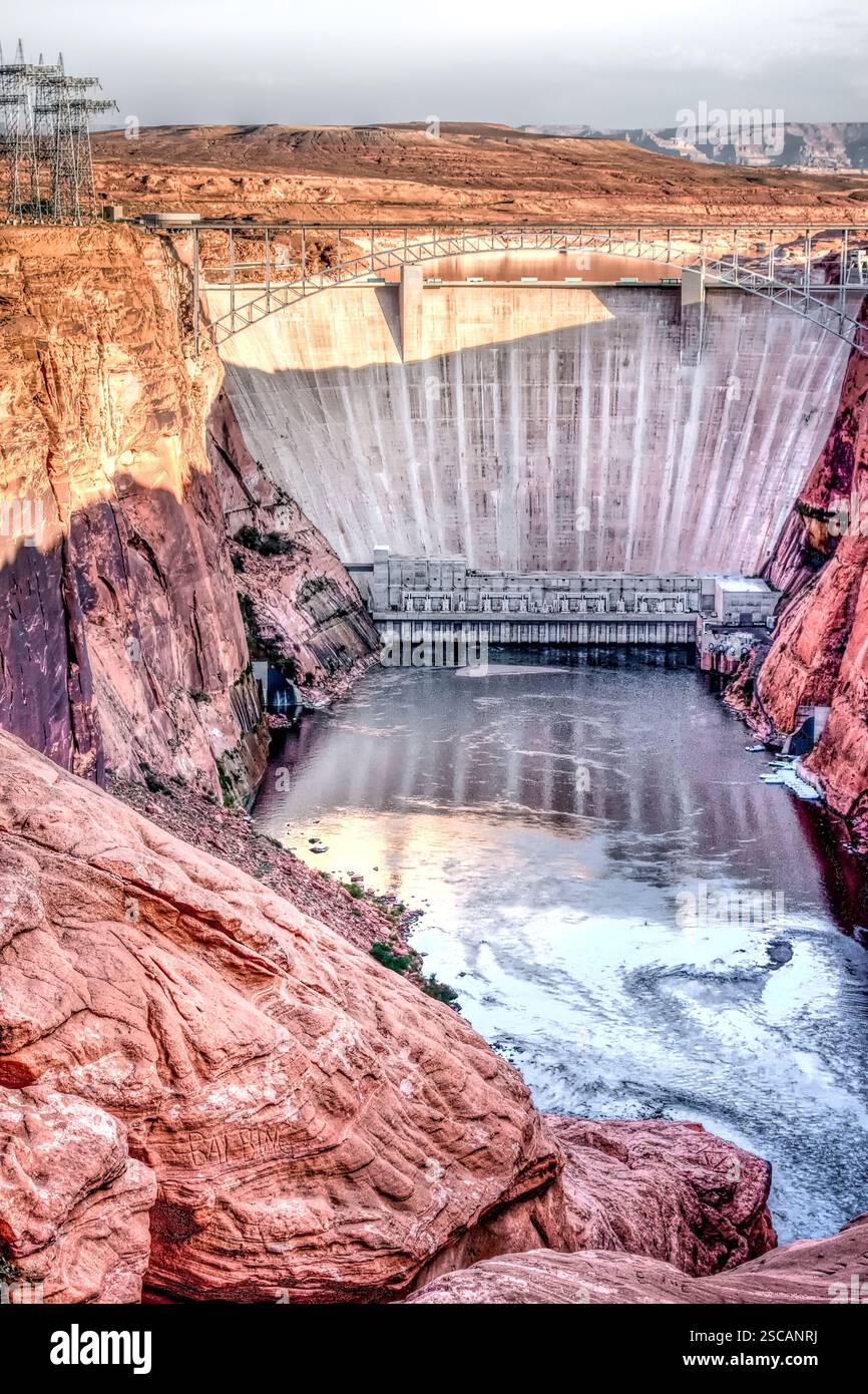 A large dam is in the middle of a rocky canyon. The water is frozen and ...