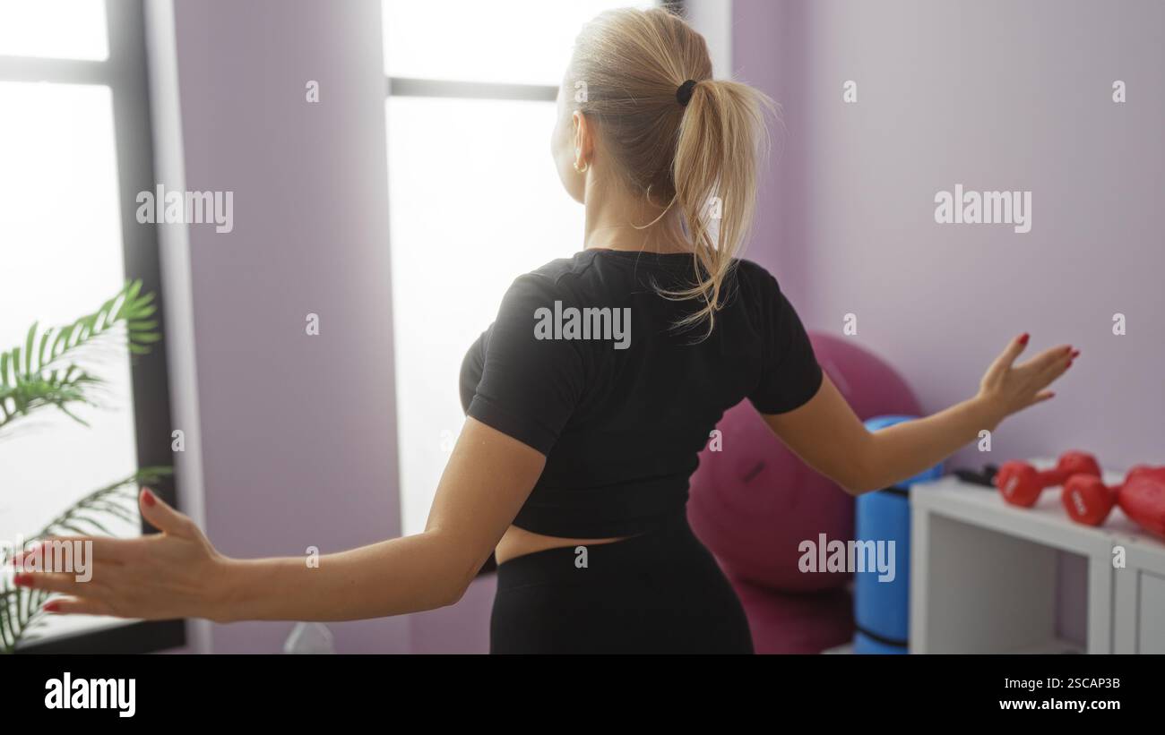 Woman exercising in gym setting, reaching arms out inside modern ...