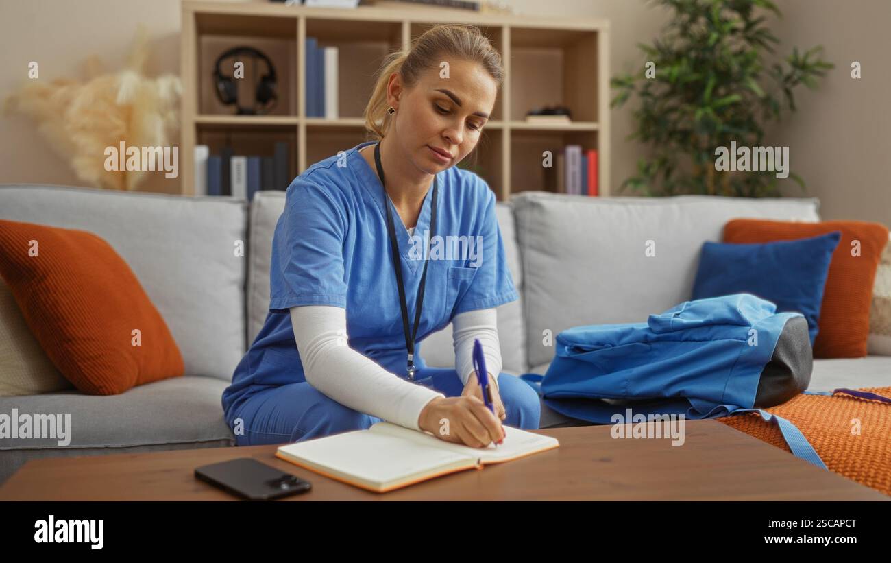 Woman wearing blue uniform writing in notebook at home with cozy living ...