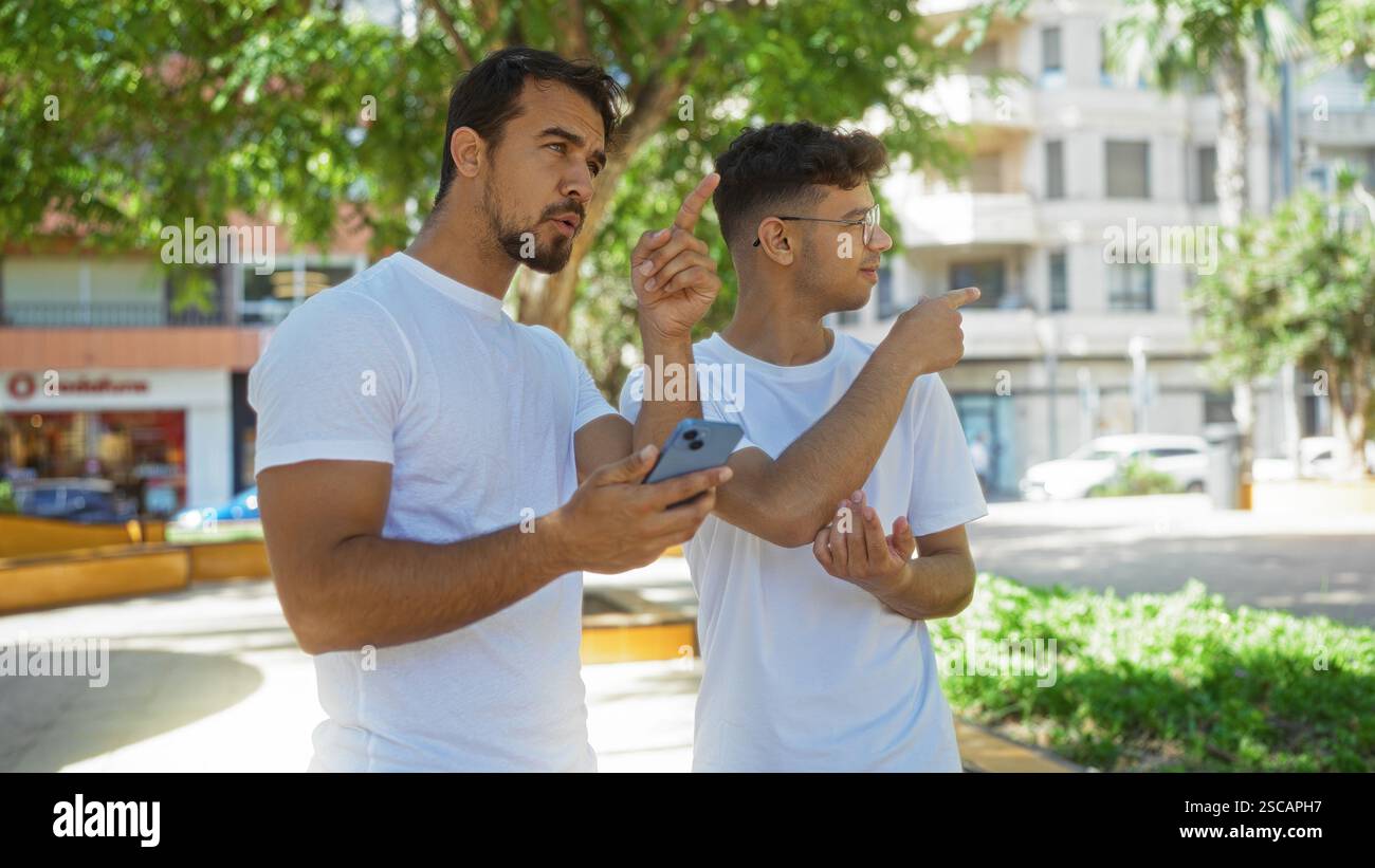 Men pointing while navigating with smartphone in a city park ...