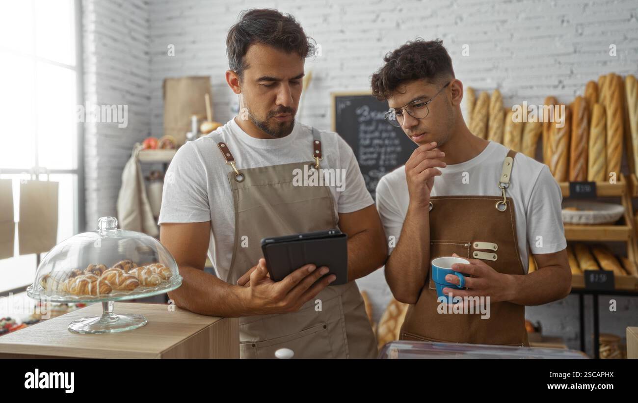 Two hispanic male bakers in a bakery shop wearing aprons are working ...