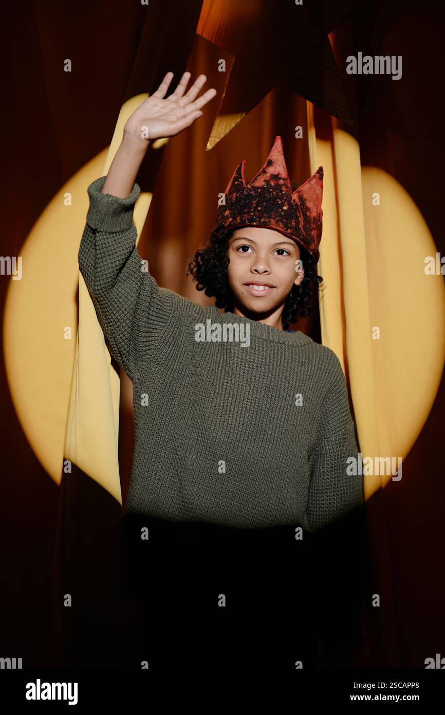 Child wearing performer's costume including a crown, waving hand in ...