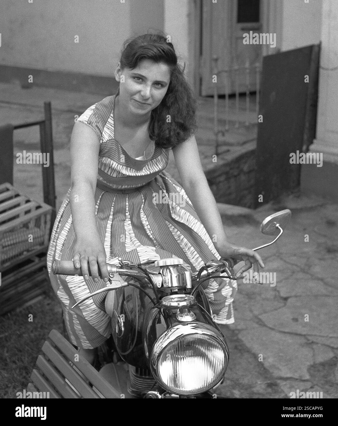 Girl wearing a dress sits on a moped in Ahlbeck Stock Photo - Alamy