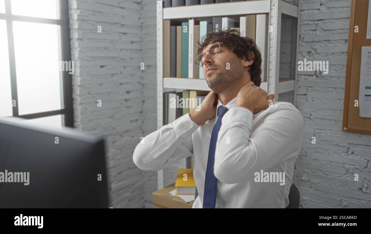 Young man experiencing neck pain in an office setting, looking ...