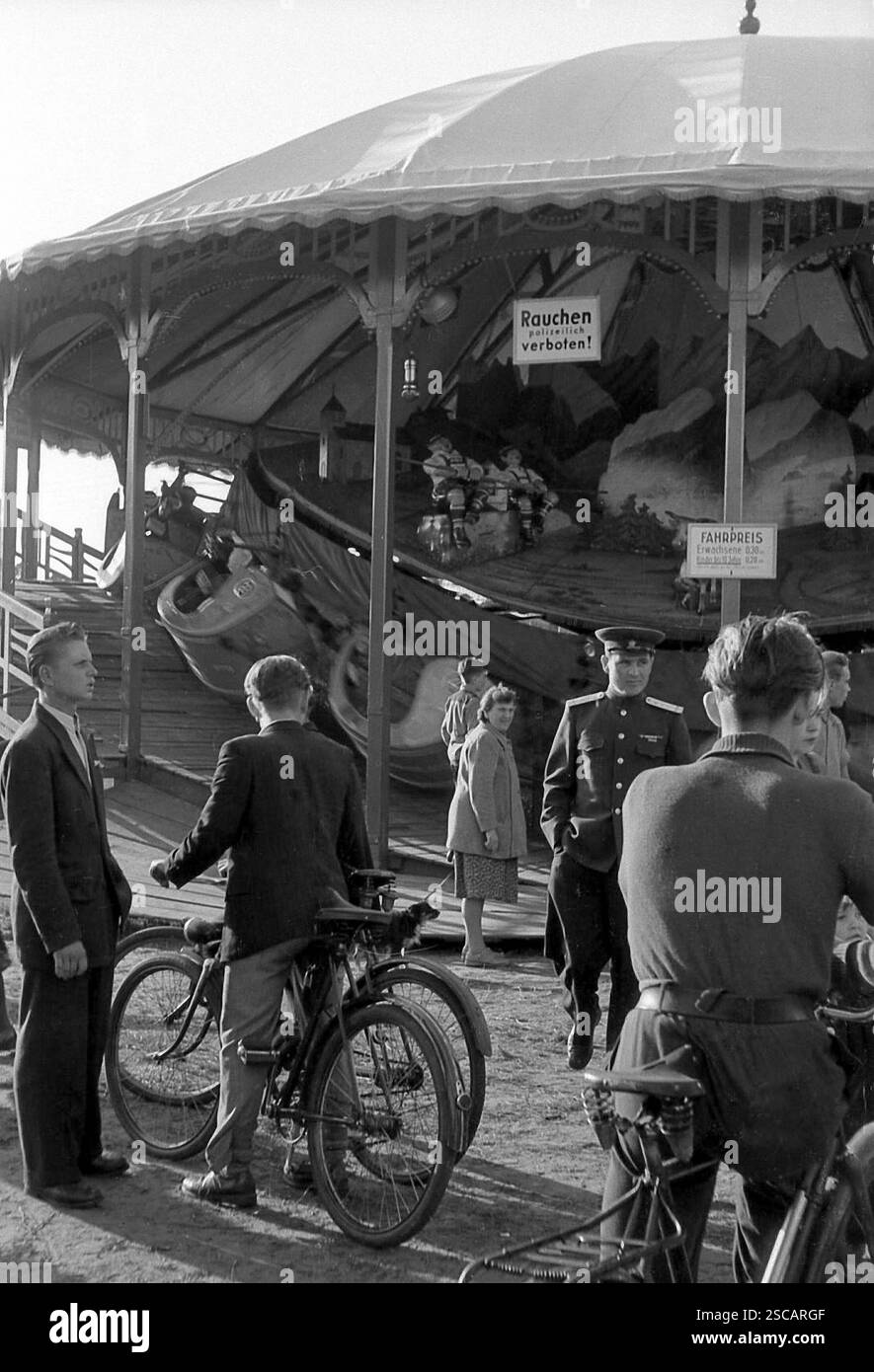 A Soviet officer in uniform stands between visitors in front of a ...