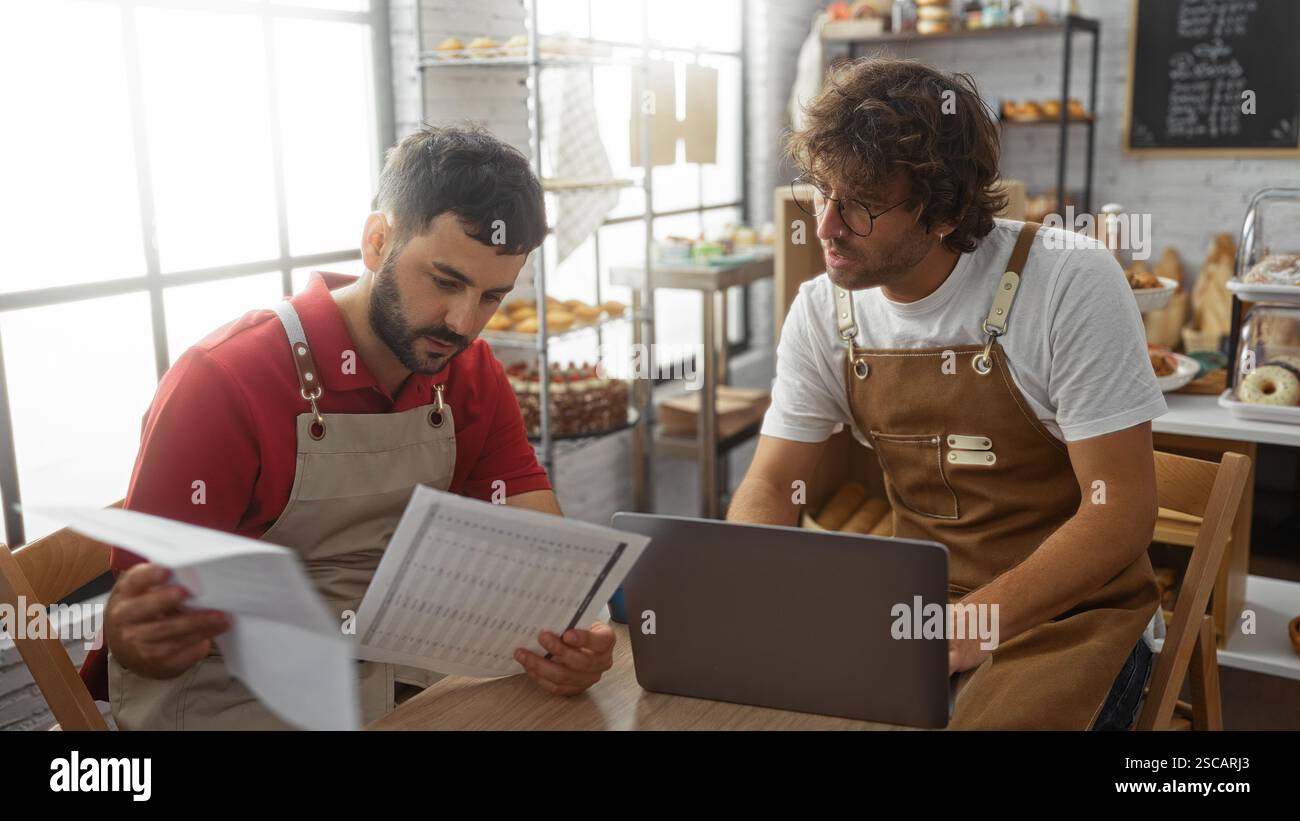 Two men, bakers working together in a bakery interior, review documents ...