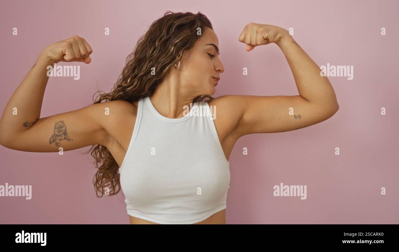Brunette woman flexing muscles while wearing a white tank top, isolated ...
