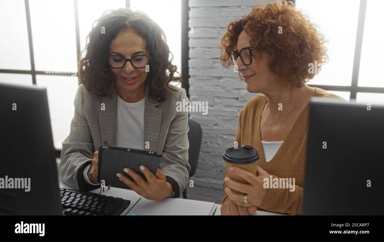 Two hispanic businesswomen collaborating in an office setting, engaging ...