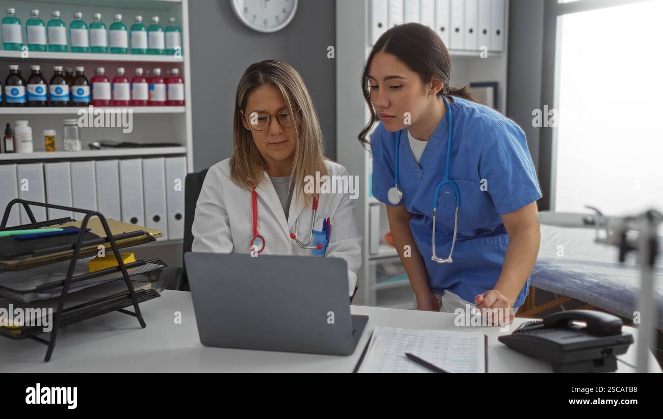 Women doctors and nurse in clinic room reviewing patient data on laptop ...