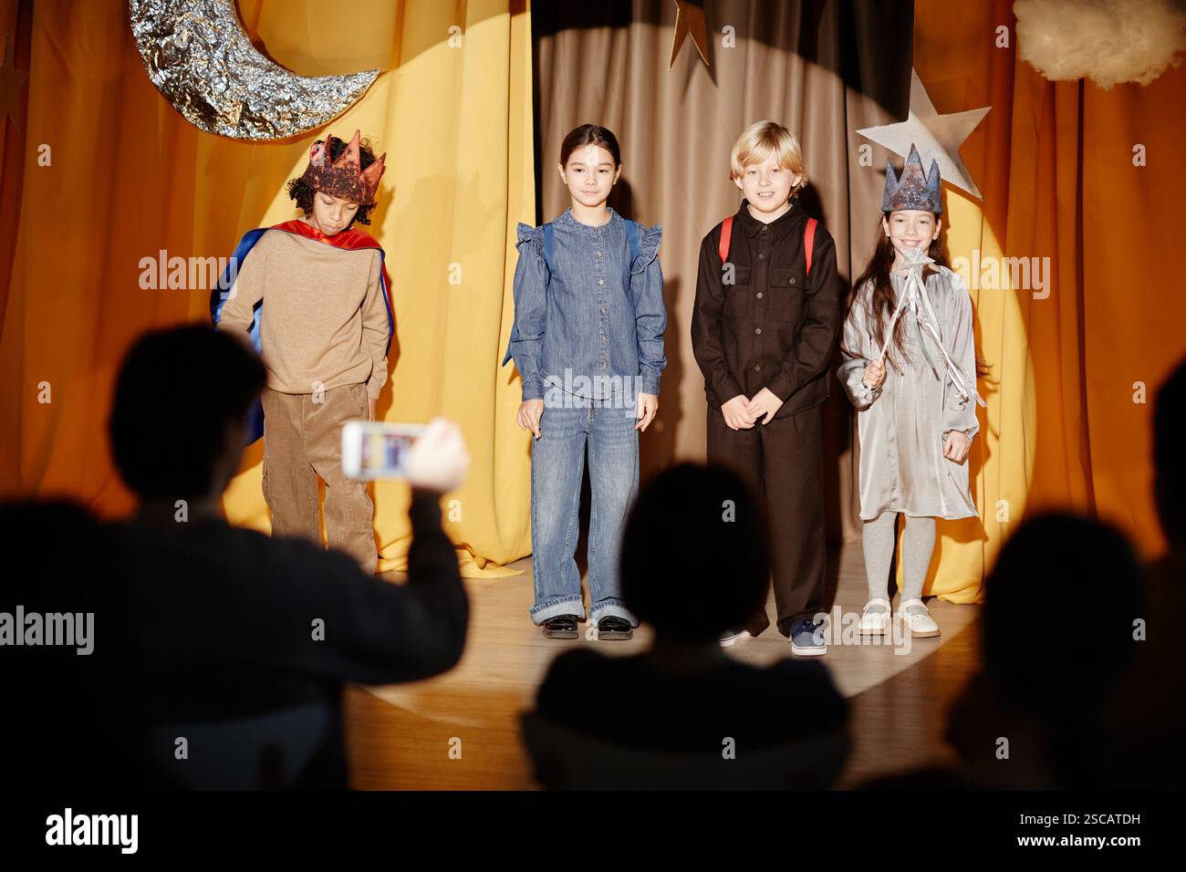 Group of children performing school play on stage with spotlight on ...