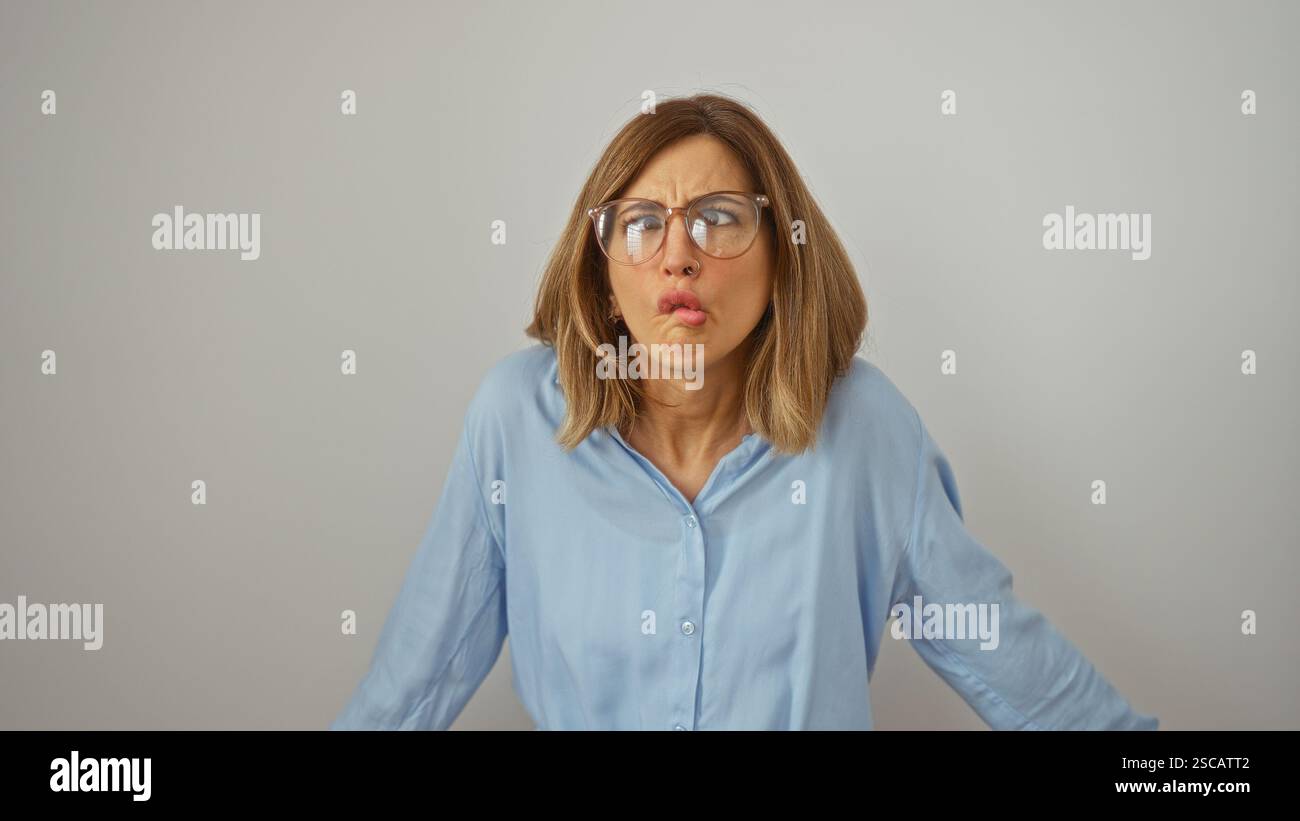 Woman making a funny face in a light blue shirt against a plain white ...