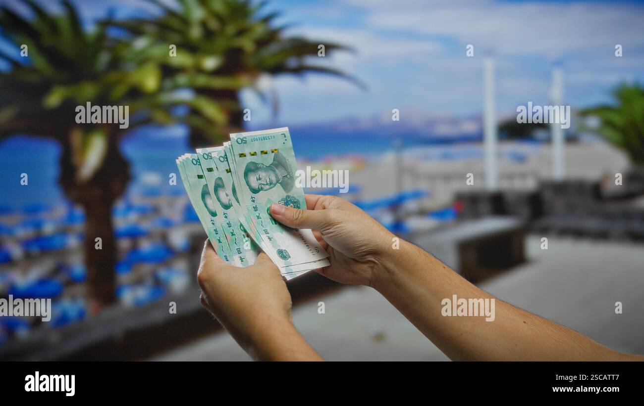 Man holding chinese yuan banknotes in hand by the seaside beach ...