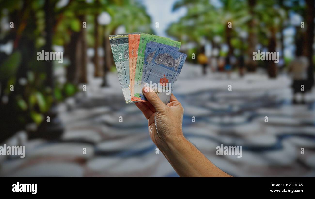 Hand holding malaysian ringgits outdoors in alicante with a blurred ...