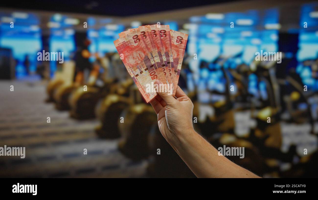 Hand holding south african rand banknotes indoors in a gym setting ...