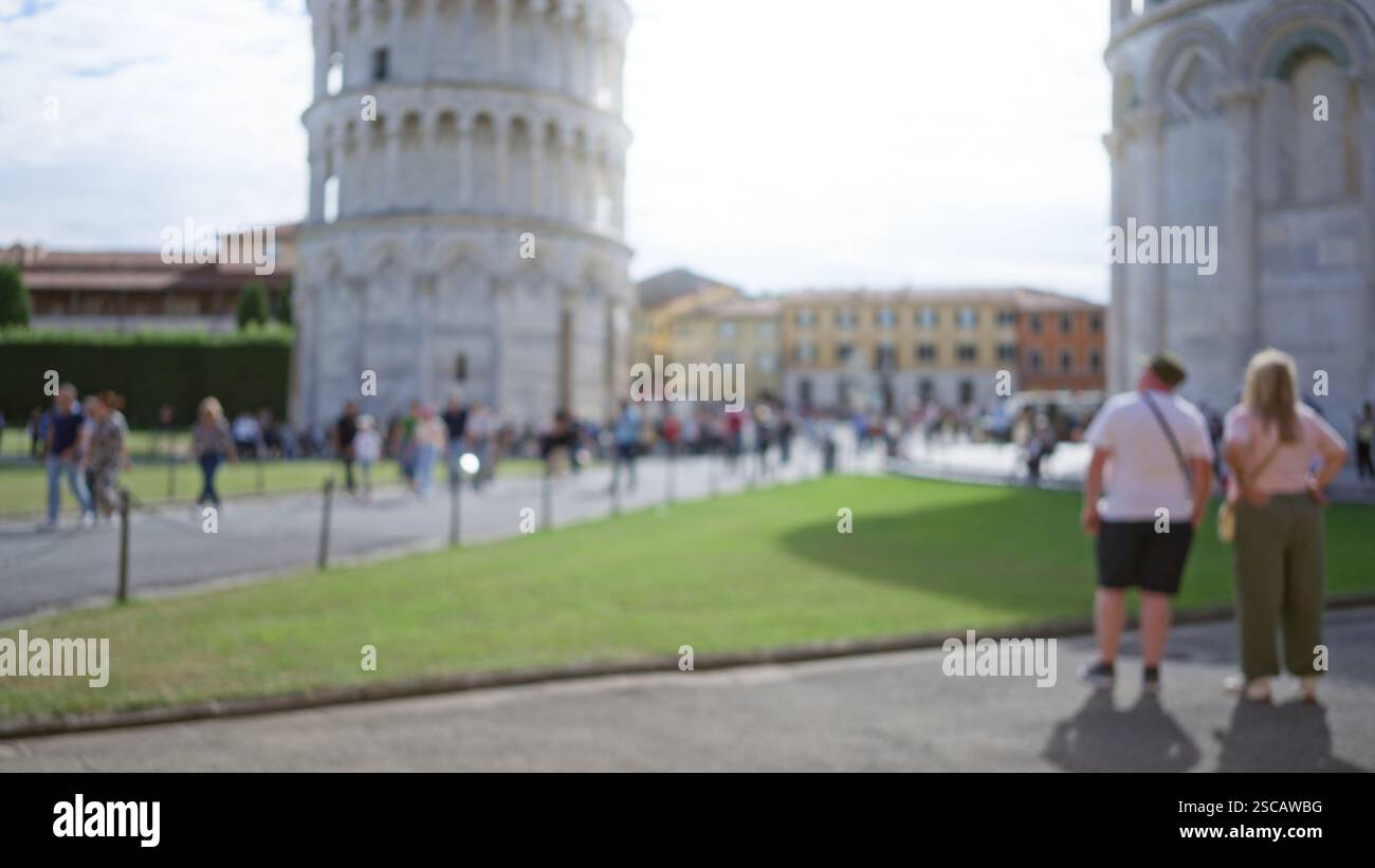 People standing defocused in front of the blurred pisa tower in a ...