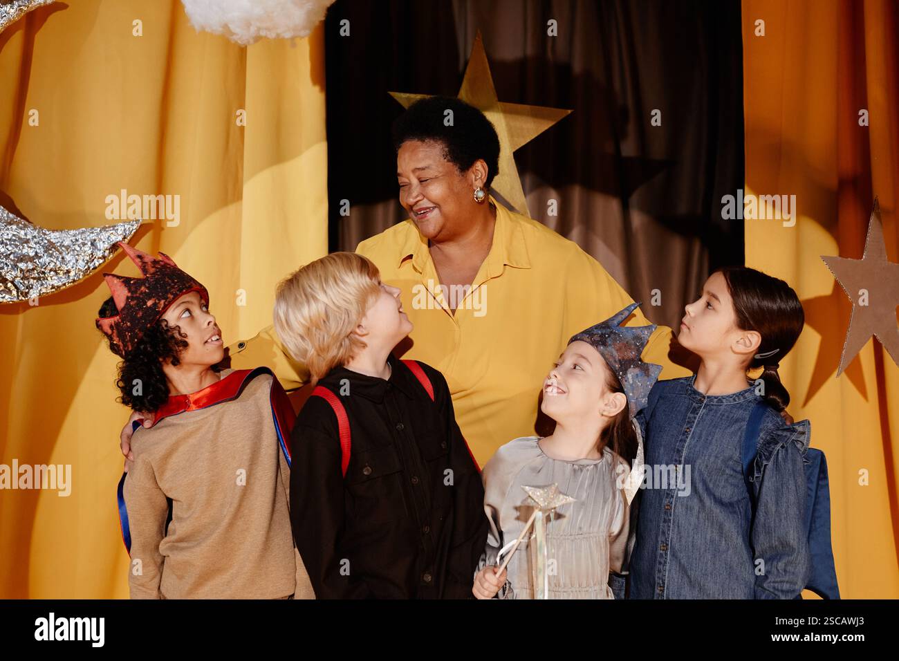 Teacher smiling warmly while interacting with group of children in ... Teacher smiling warmly while interacting with group of children in ...