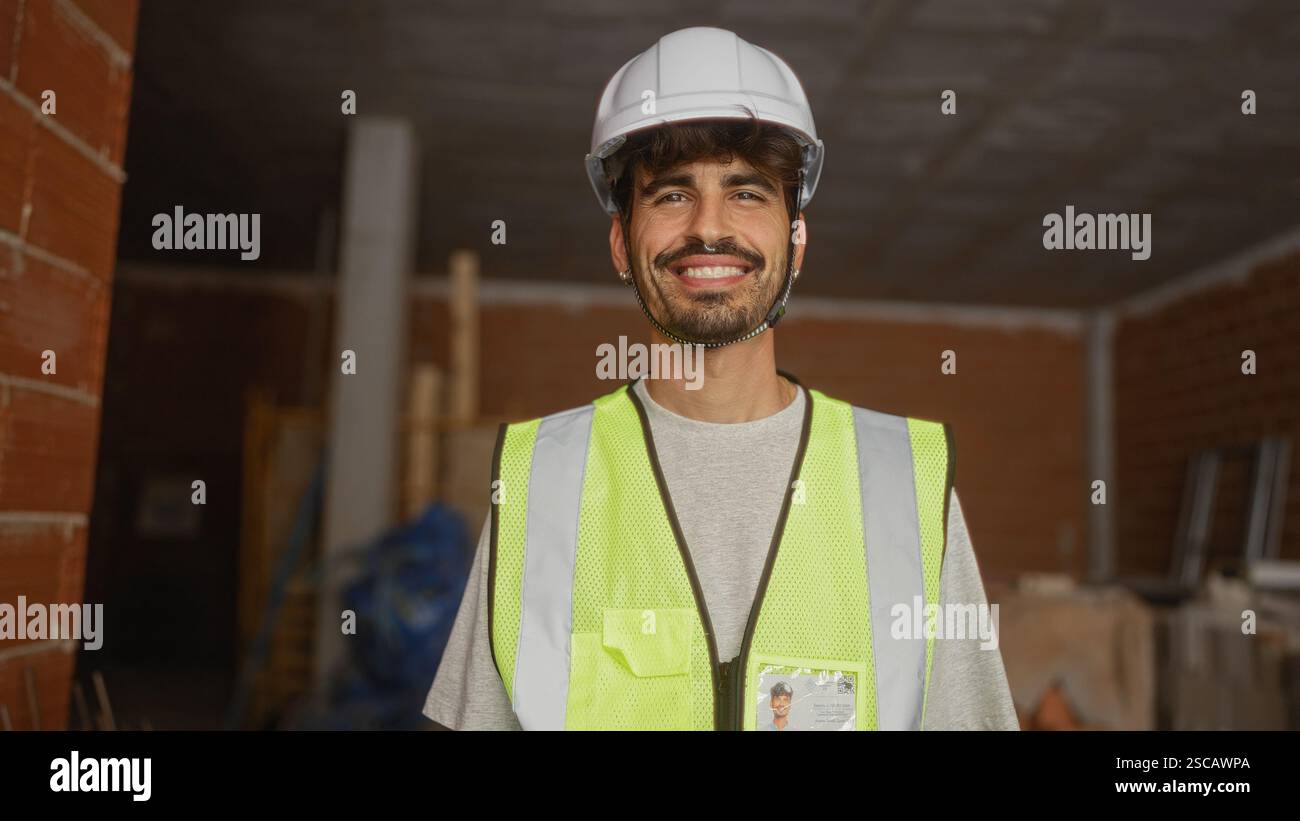 Hispanic man in a safety vest and hard hat smiles at a construction ...