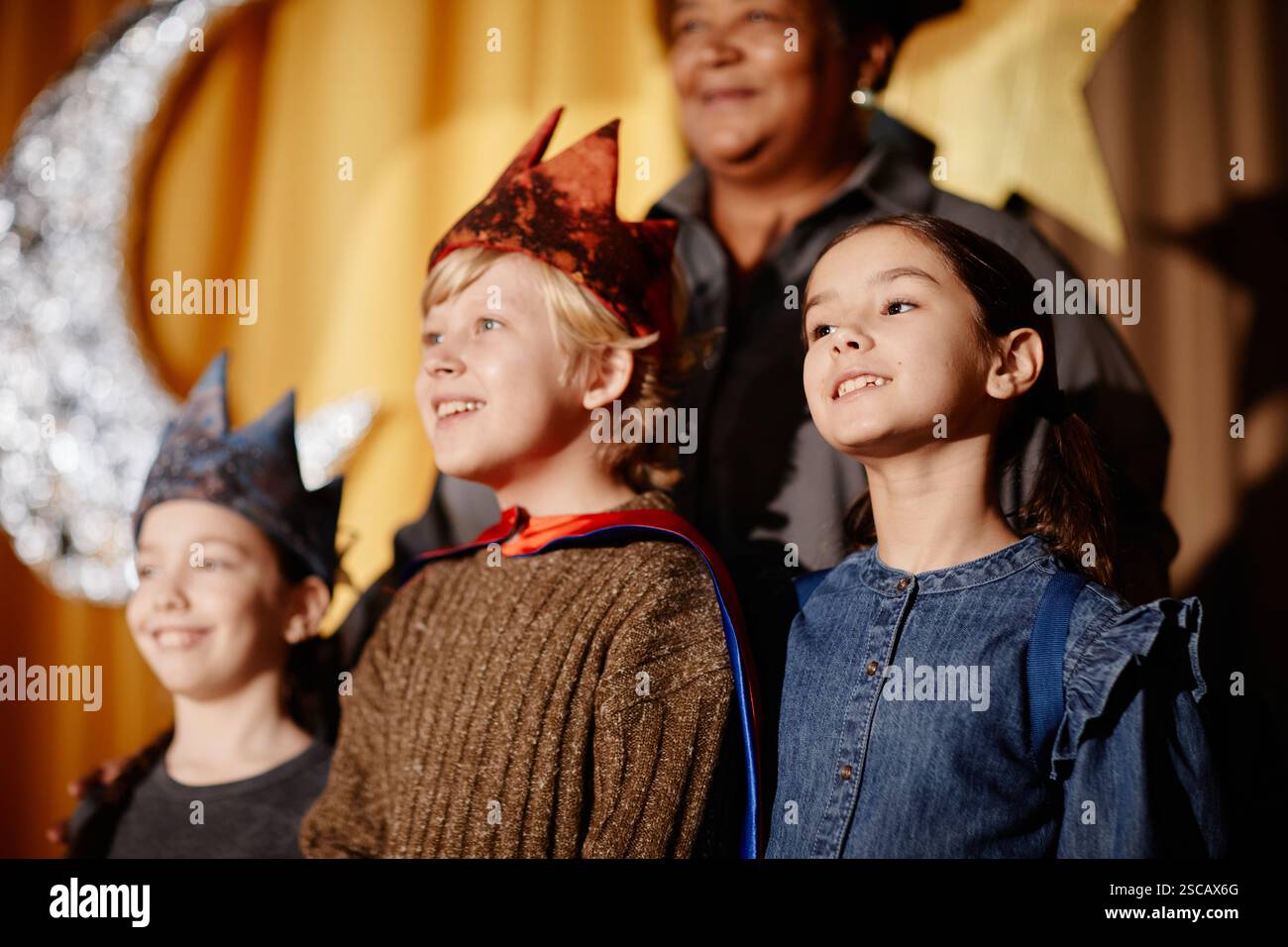 Three children wearing costumes standing on stage during school play in ...