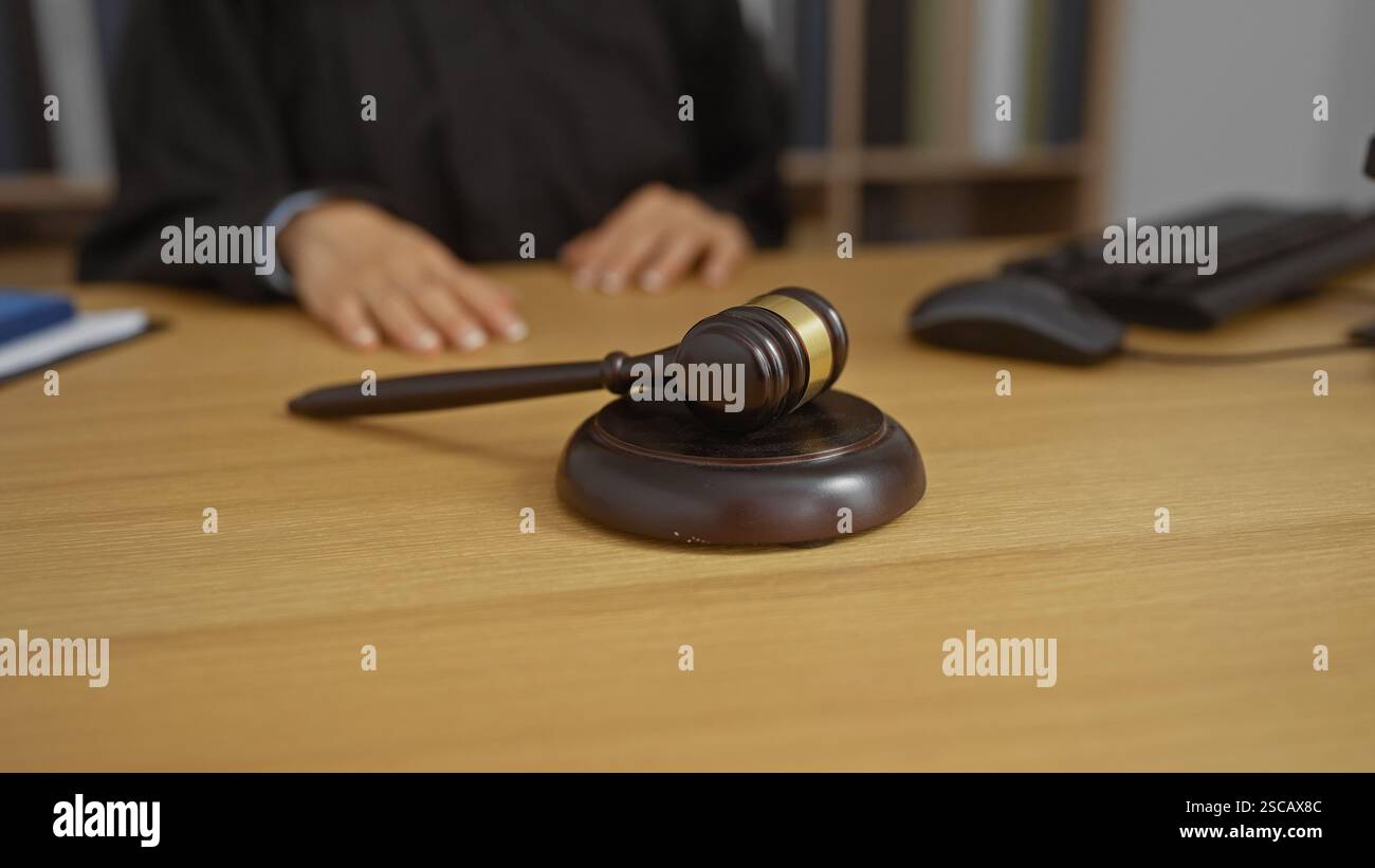 Female judge's hands rest on a desk with a gavel in focus, symbolizing ...