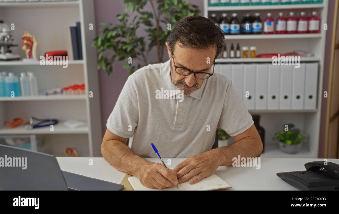 Mature man writing at desk in pharmacy shop interior with medicine and ...