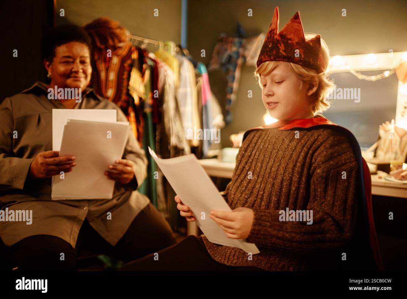 Scene depicting actor wearing crown and cape receiving guidance from ...