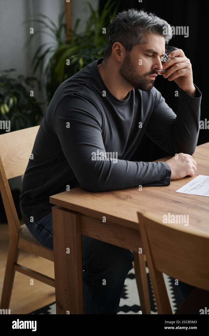 A thoughtful man rests his forehead on his hand, surrounded by greenery ...