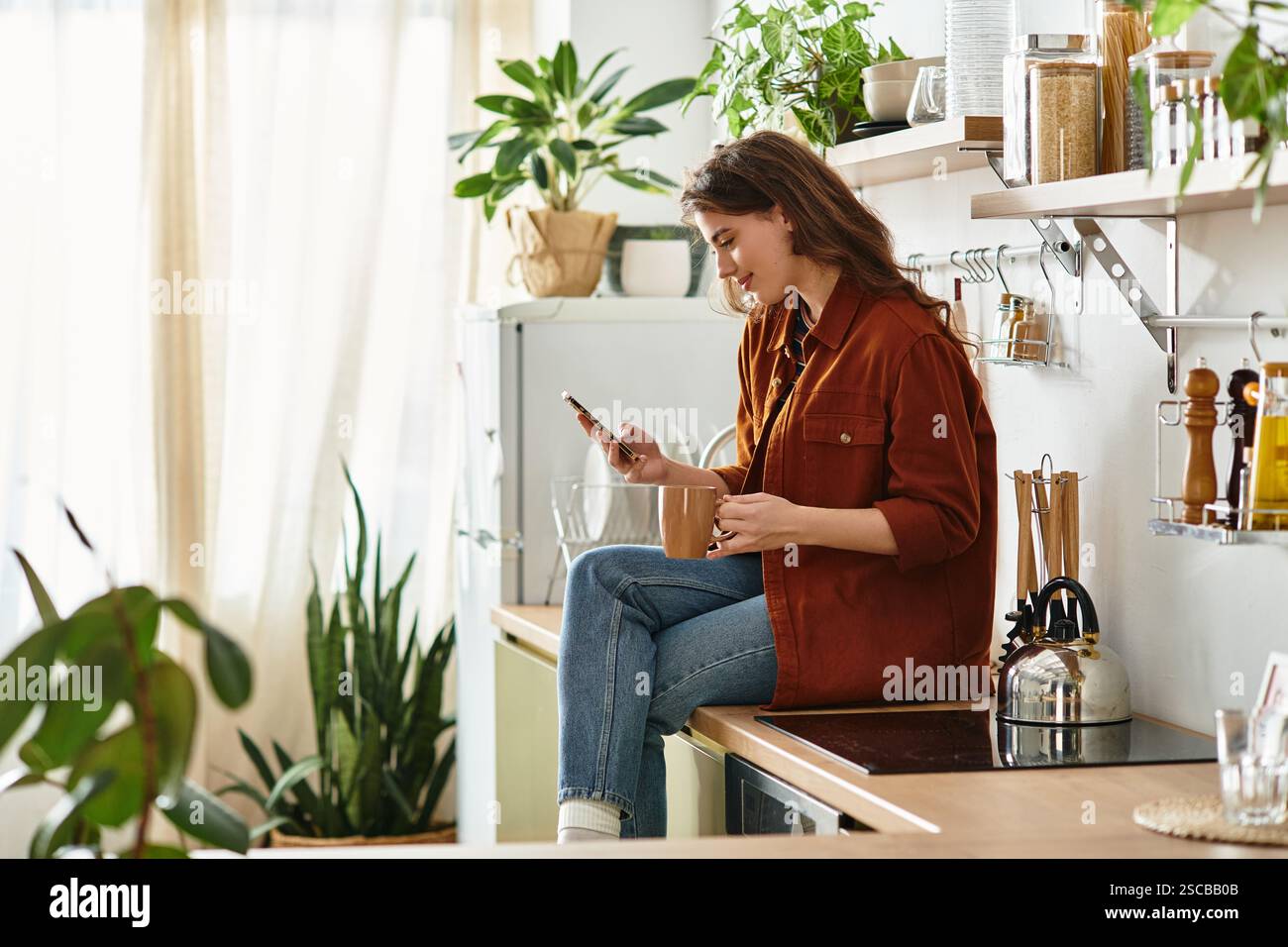 A woman sits comfortably on a kitchen counter, sipping a warm drink ...