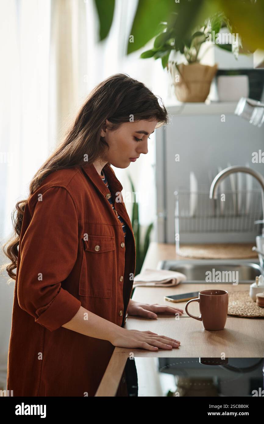 A woman stands pensively by the kitchen counter, lost in deep thoughts ...