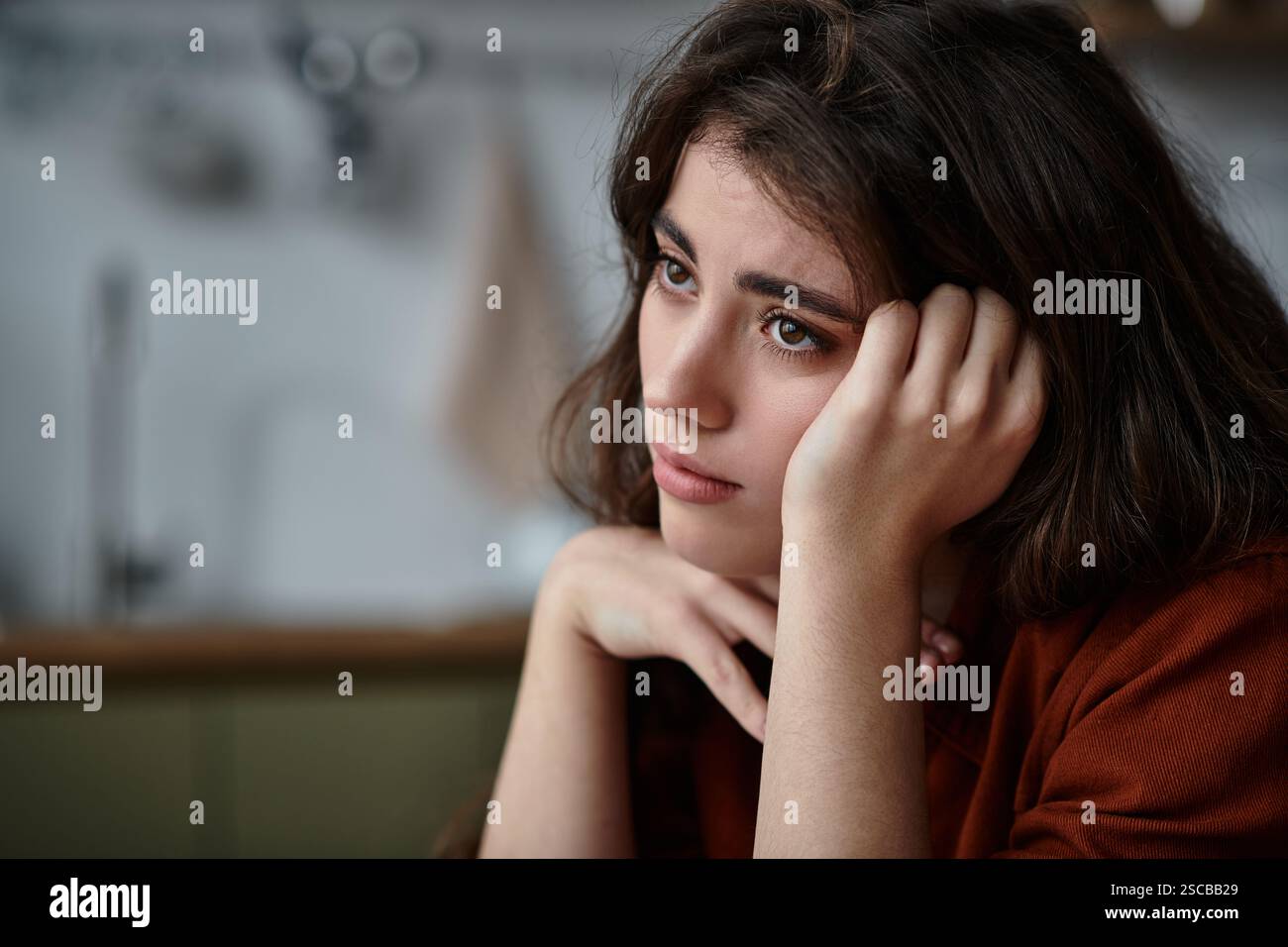 Woman appears lost in thought, expressing deep emotions in a warm ...