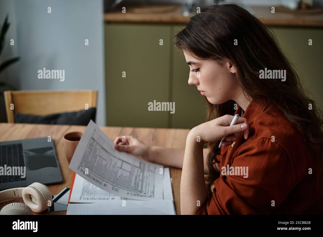 A woman sits at a table, absorbed in her paperwork, reflecting feelings ...