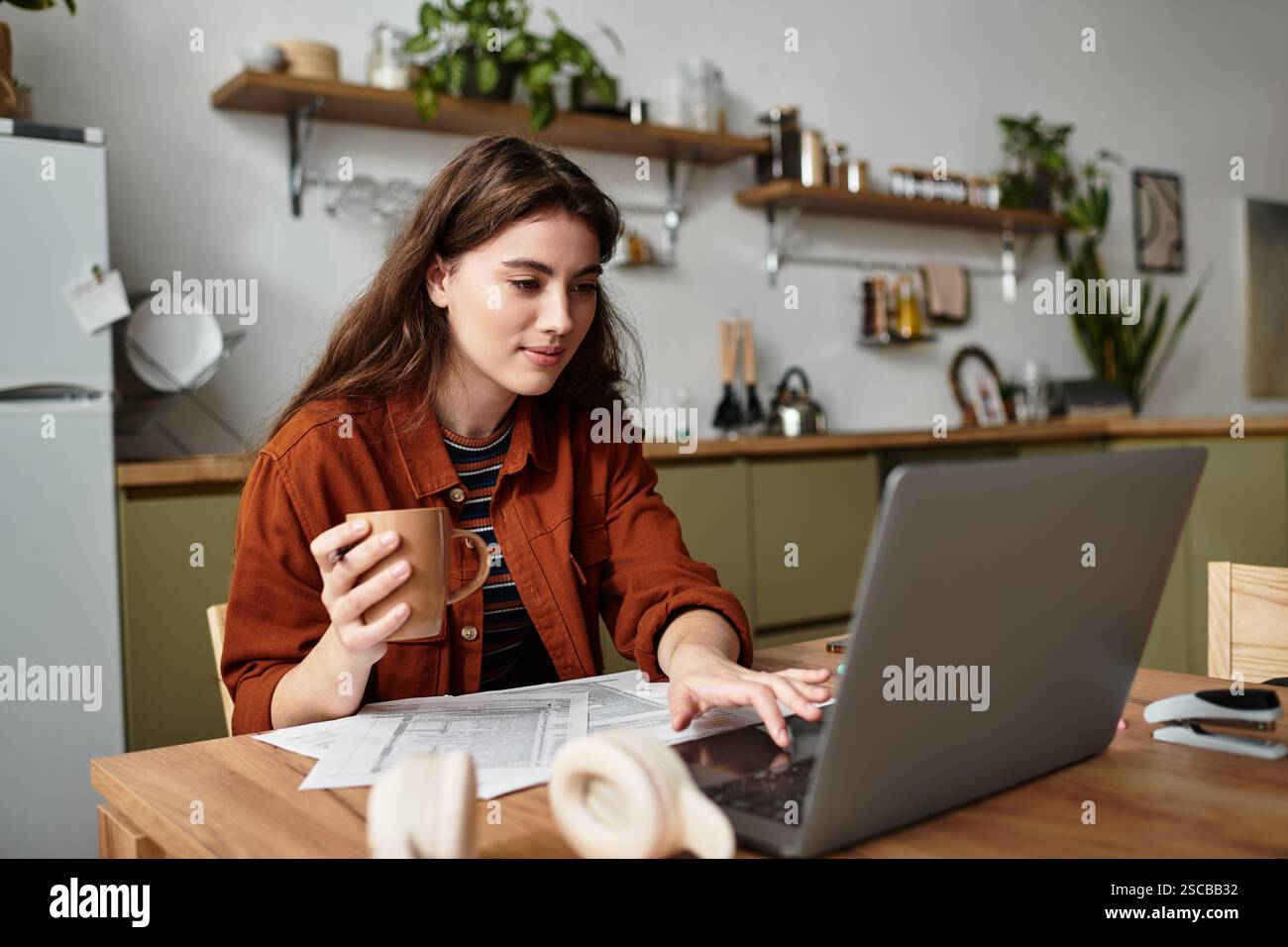 A woman quietly engages with her laptop, seeking comfort in her creativity amid depression Stock ...