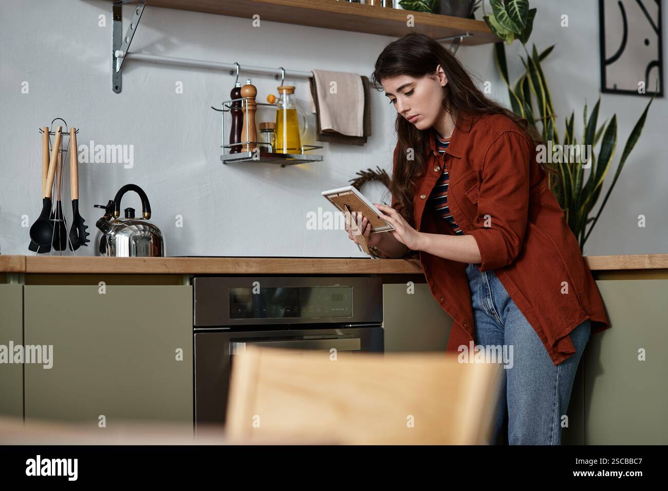 In a warm kitchen, a woman leans against the counter, deep in thought ...