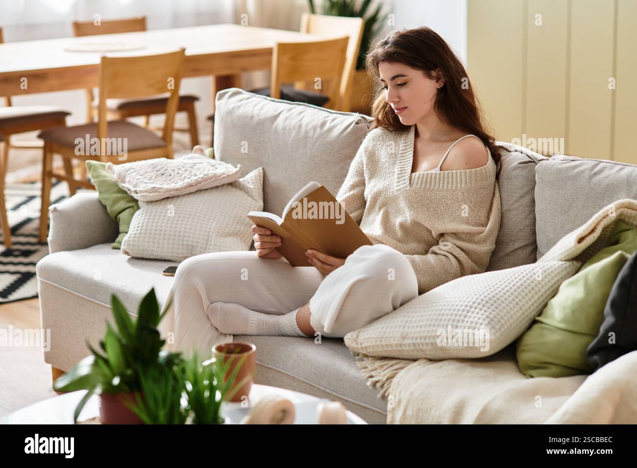 A woman sits quietly on a couch, immersed in a book, reflecting on her ...