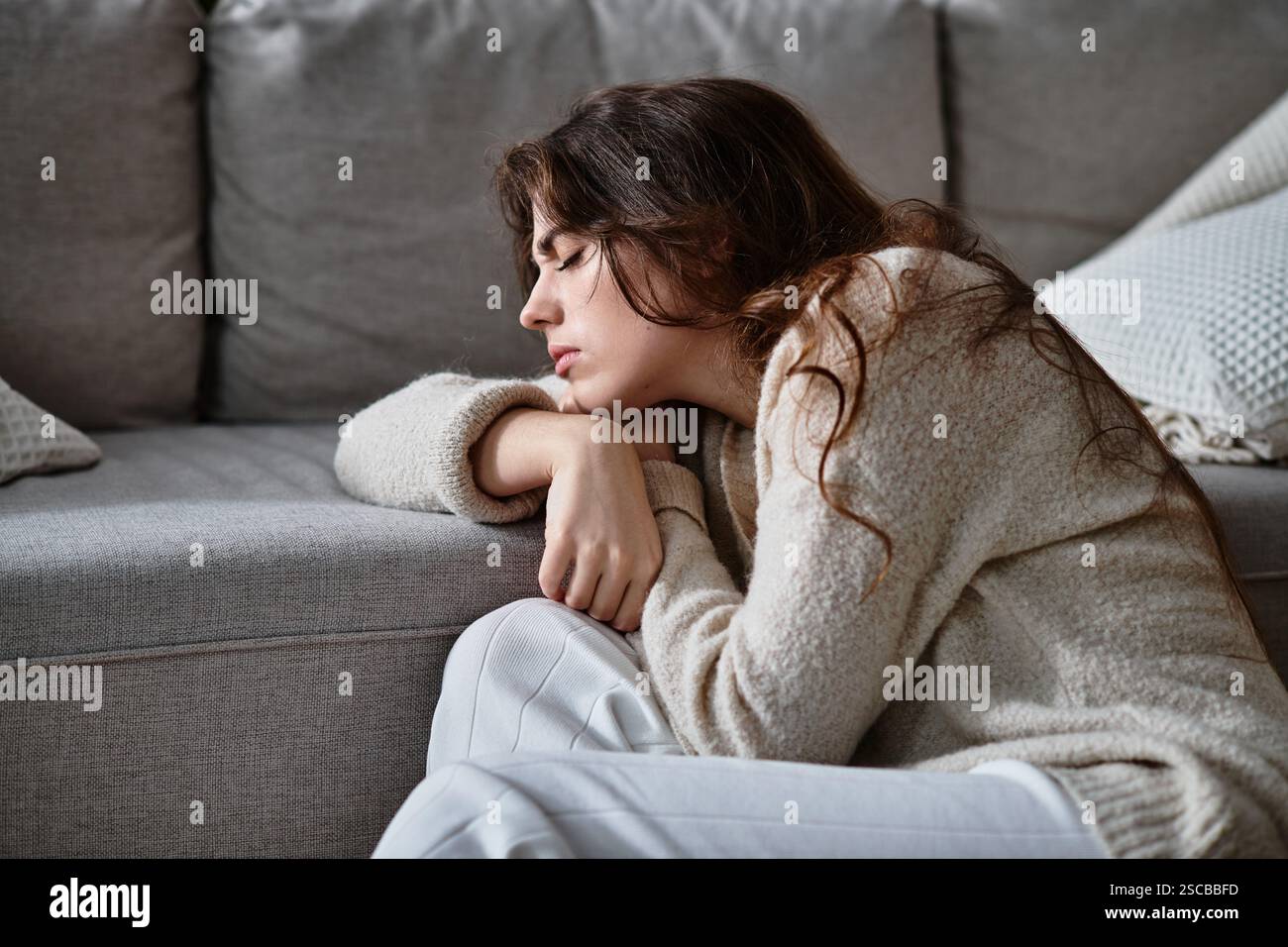 A woman with melancholy rests her head on her arms, overcome by ...