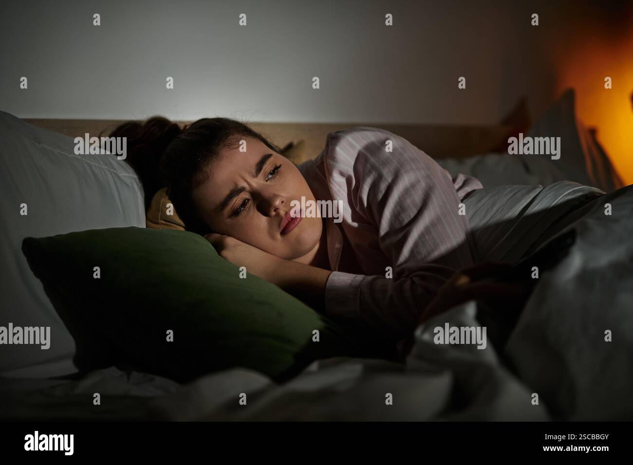 A woman lies awake in bed, deep in thought as she battles her inner ...