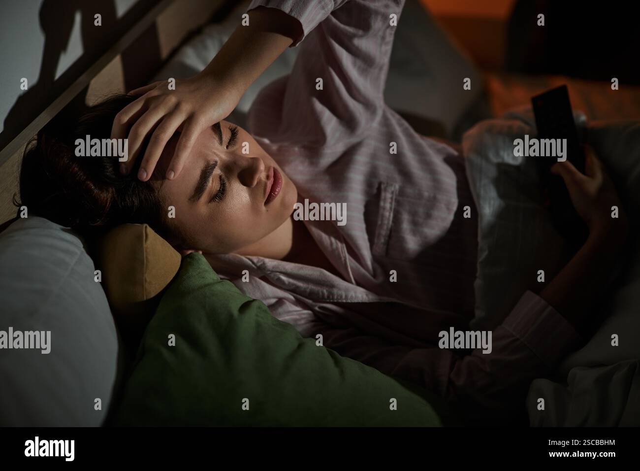 A woman lies awake in bed, burdened by heavy thoughts and emotions in ...