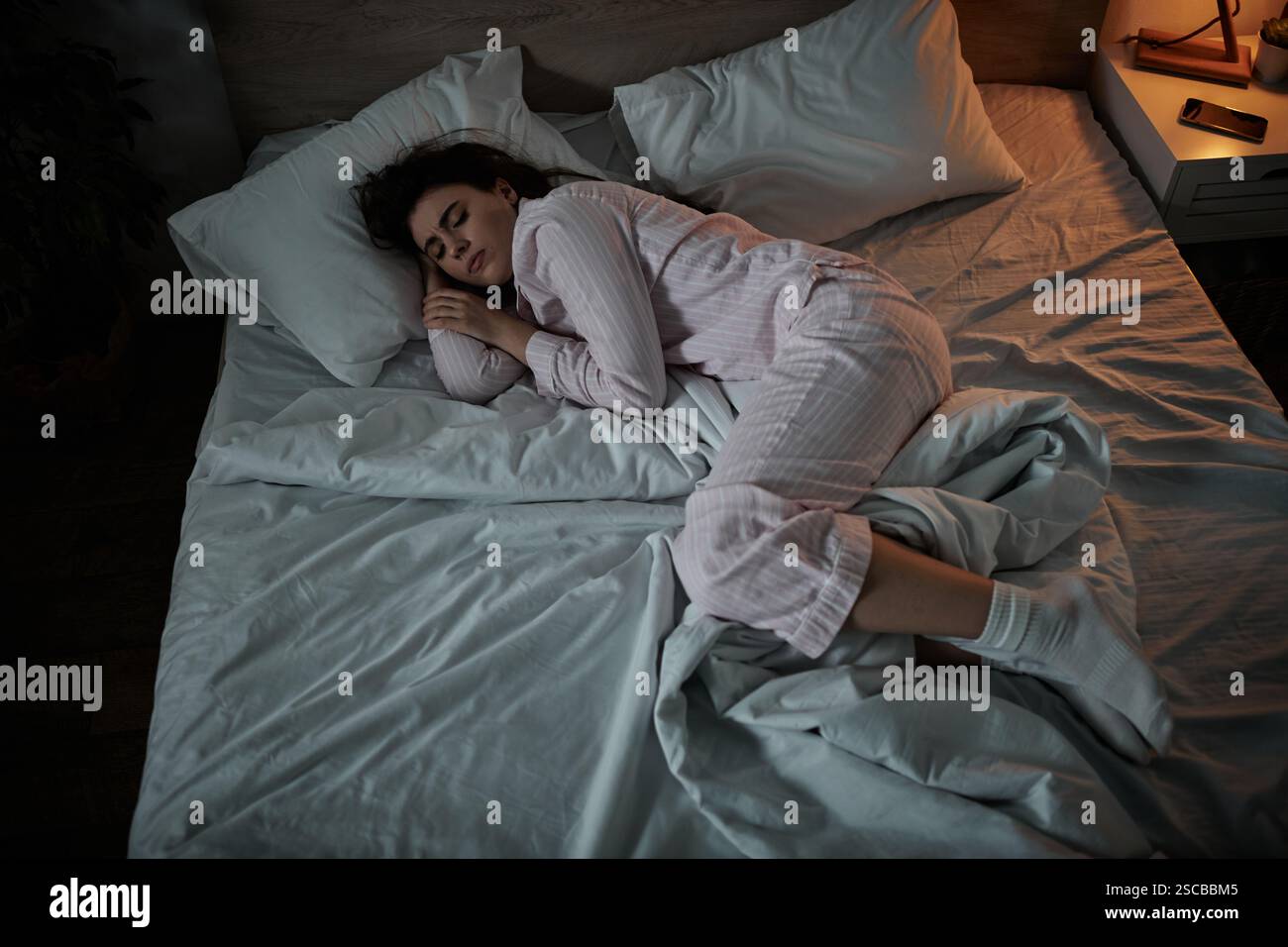 A woman lies curled up in bed, battling her inner turmoil and feelings ...