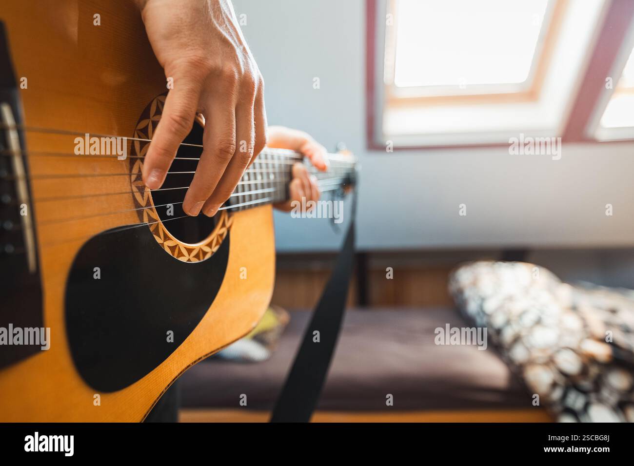 Close-up perspective of an acoustic guitar being played, with fingers ...