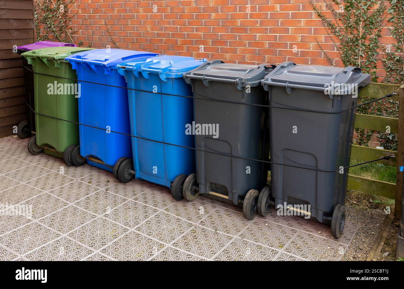 UK recycling wheelie bins of different colors lined up in garden ...
