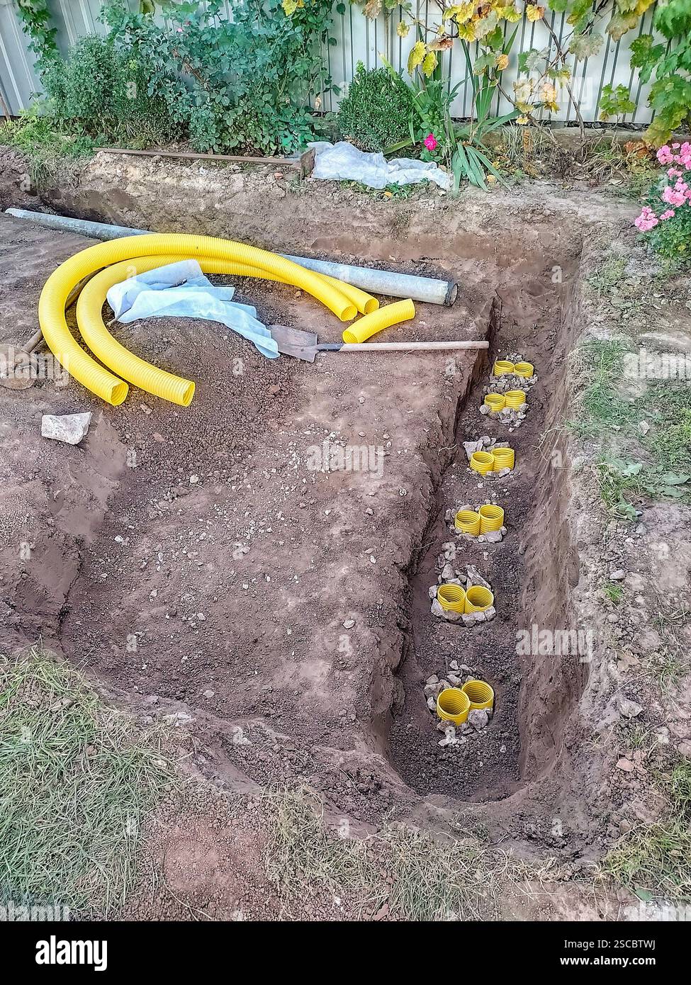 Drainage pipes being installed in a backyard trench as part of a home ...