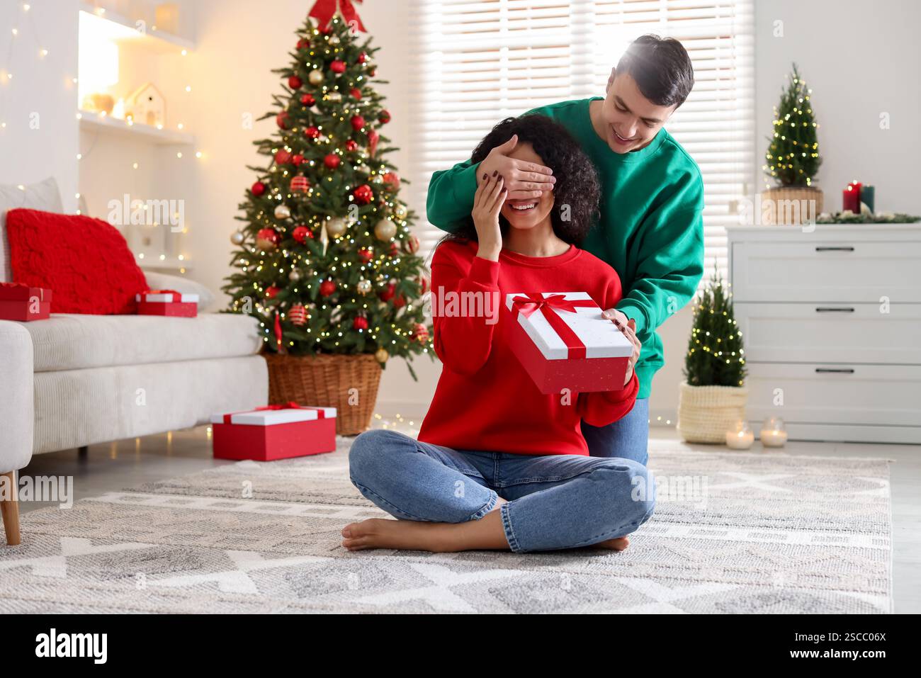 Happy man surprising girlfriend with Christmas gift at home Stock Photo ...