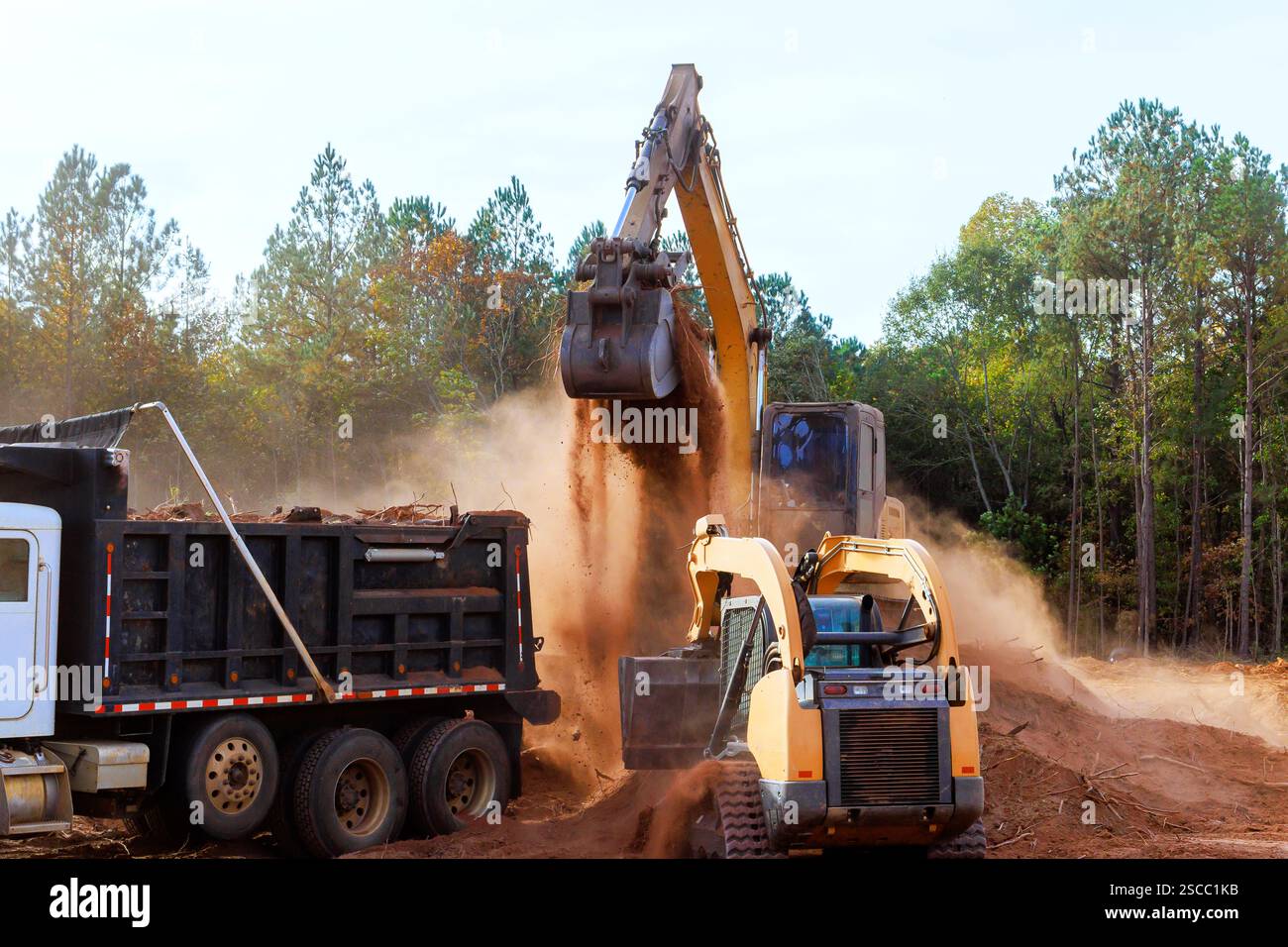 Heavy machinery moves soil, debris on construction site surrounded by ...